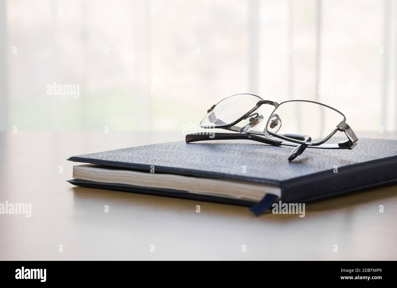 Glasses on a book and table with nature background Stock Photo - Alamy