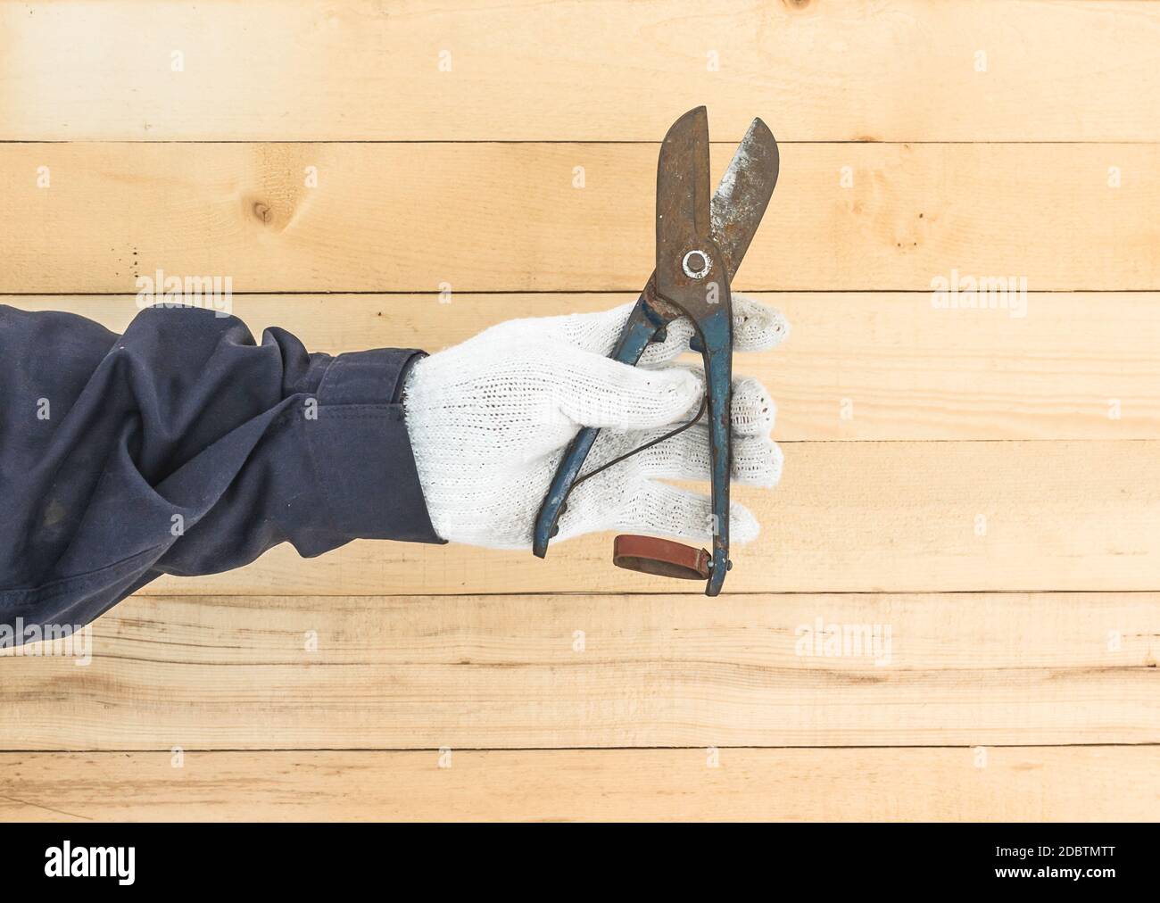 Working hand in glove holding a pliers with wall wood background Stock ...