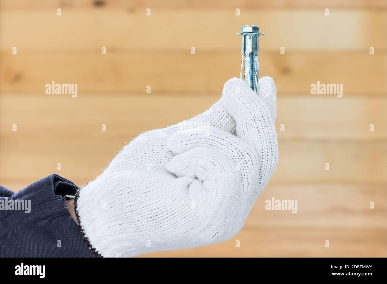 Working hand in glove holding metal anchor bolts with wall wood ...
