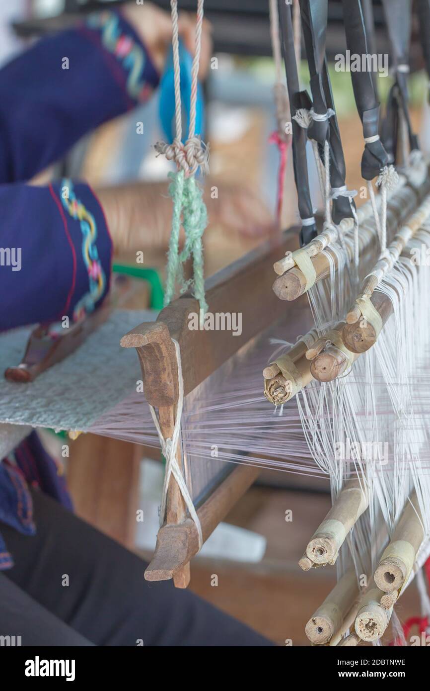 Close up of woman weaving white pattern on loom in Chiang Mai Thailand ...