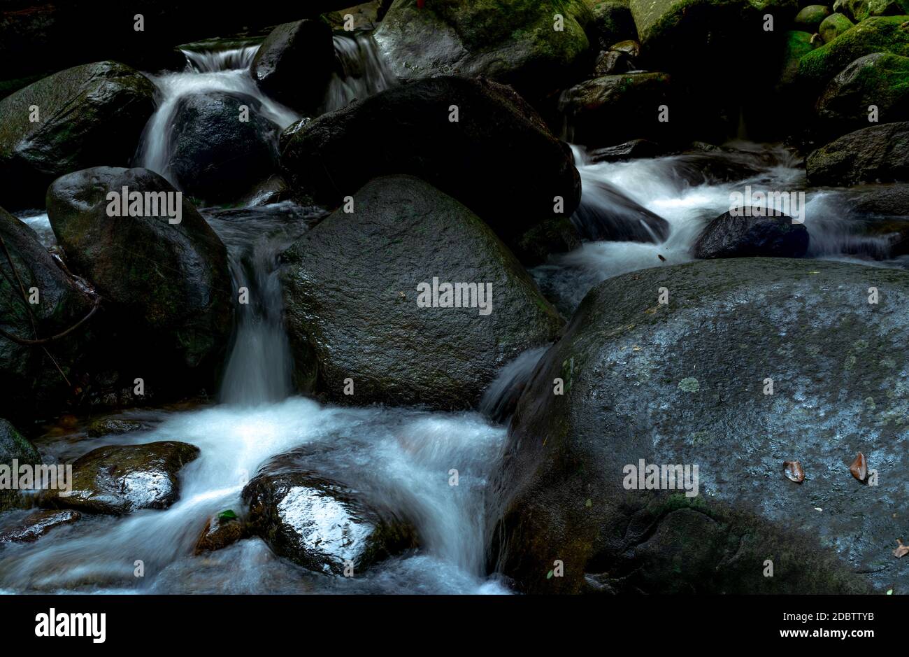 Black rock at waterfall with green moss and sunshine on rock. Waterfall ...