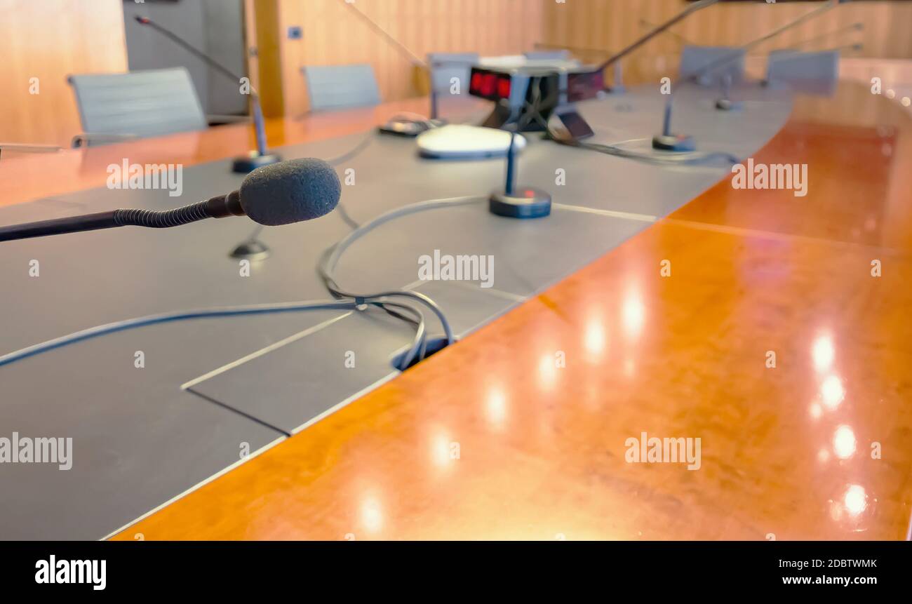 Microphone on a wooden table and empty chairs in a boardroom ...