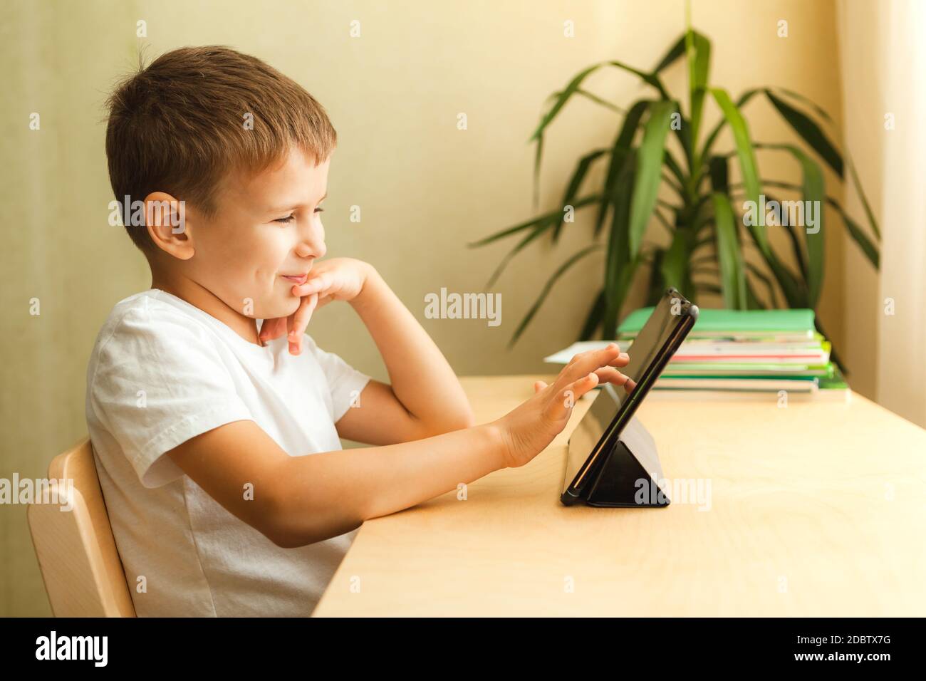 Happy boy drawing on tablet sitting by desk at home. Child using ...