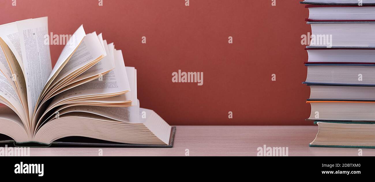 A large, thick hardcover book is lying on a light wood table. The book ...