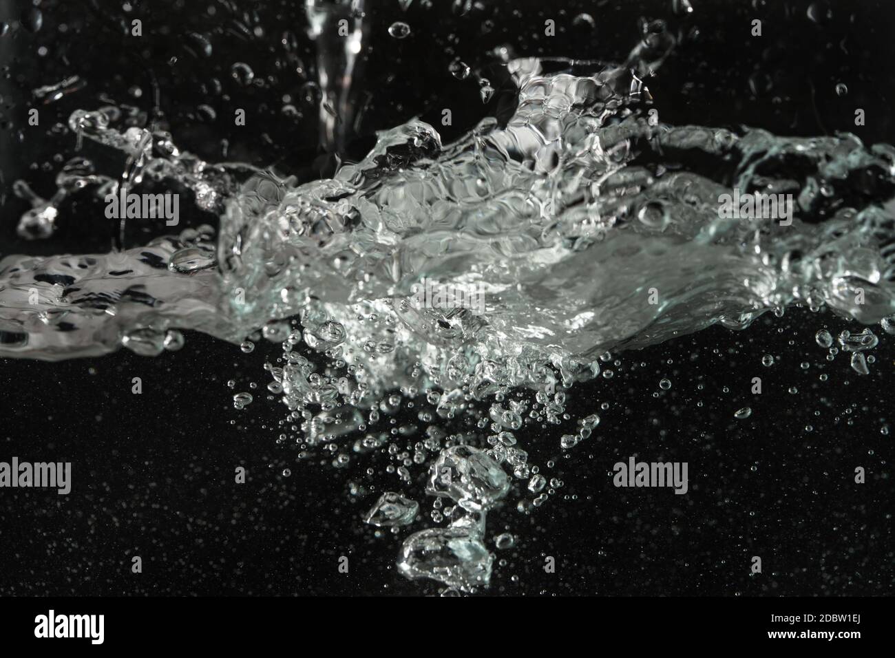 Water splashing as it's poured into aquarium tank, black background ...