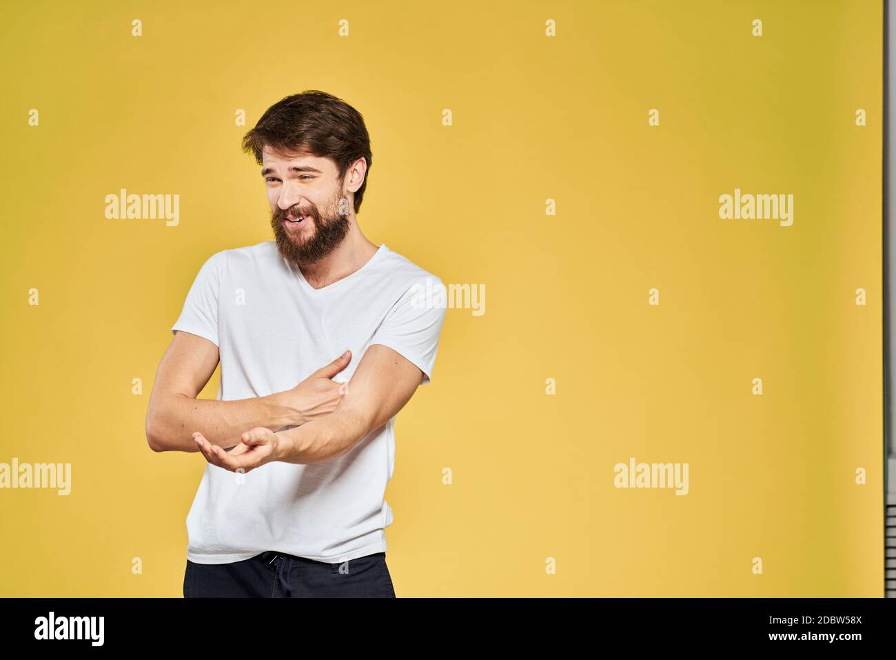 Man gesturing with hands emotions lifestyle white t-shirt yellow isolated background Stock Photo ...