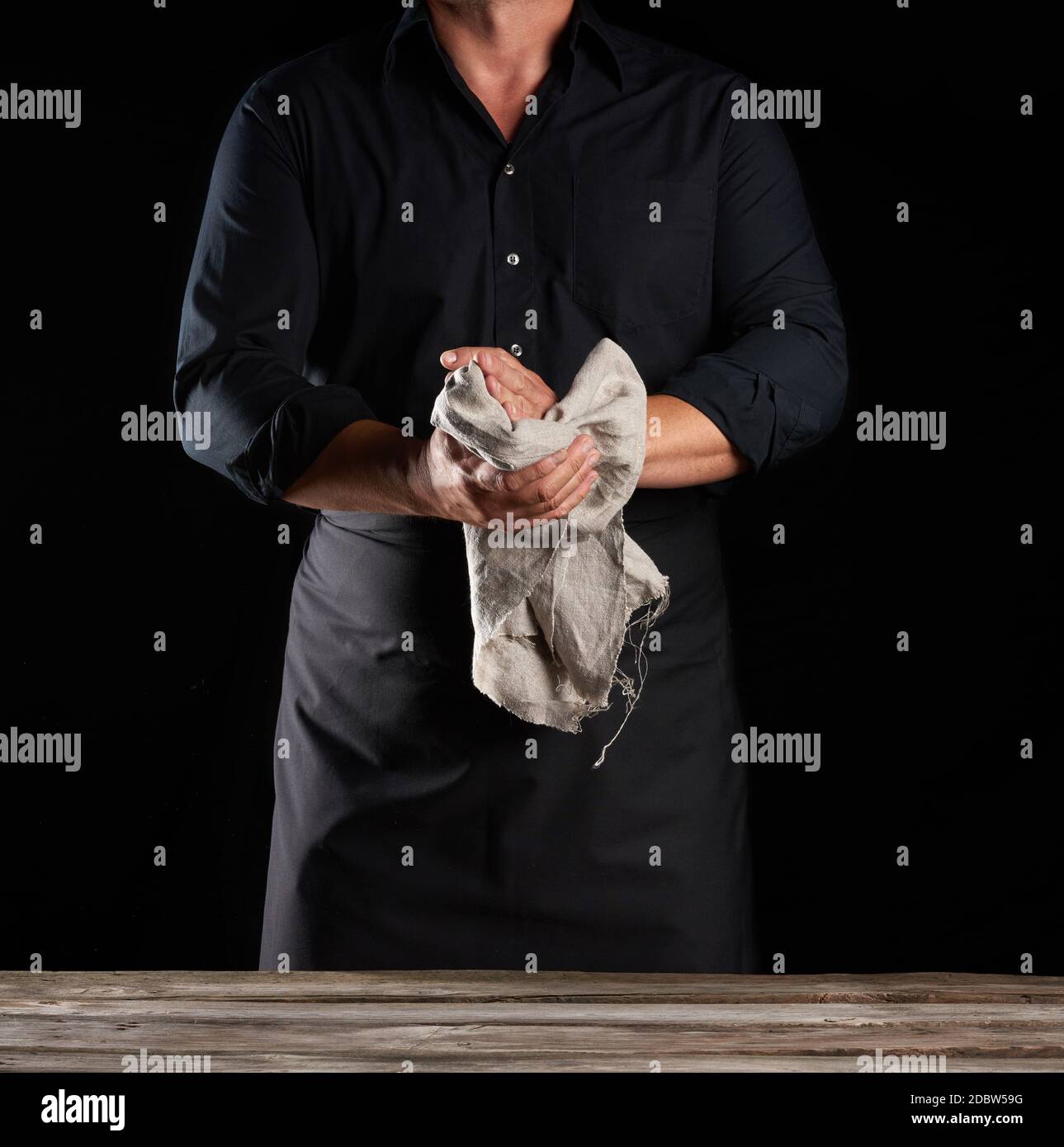 man in black uniform holds gray linen rag and wipes his hands over ...