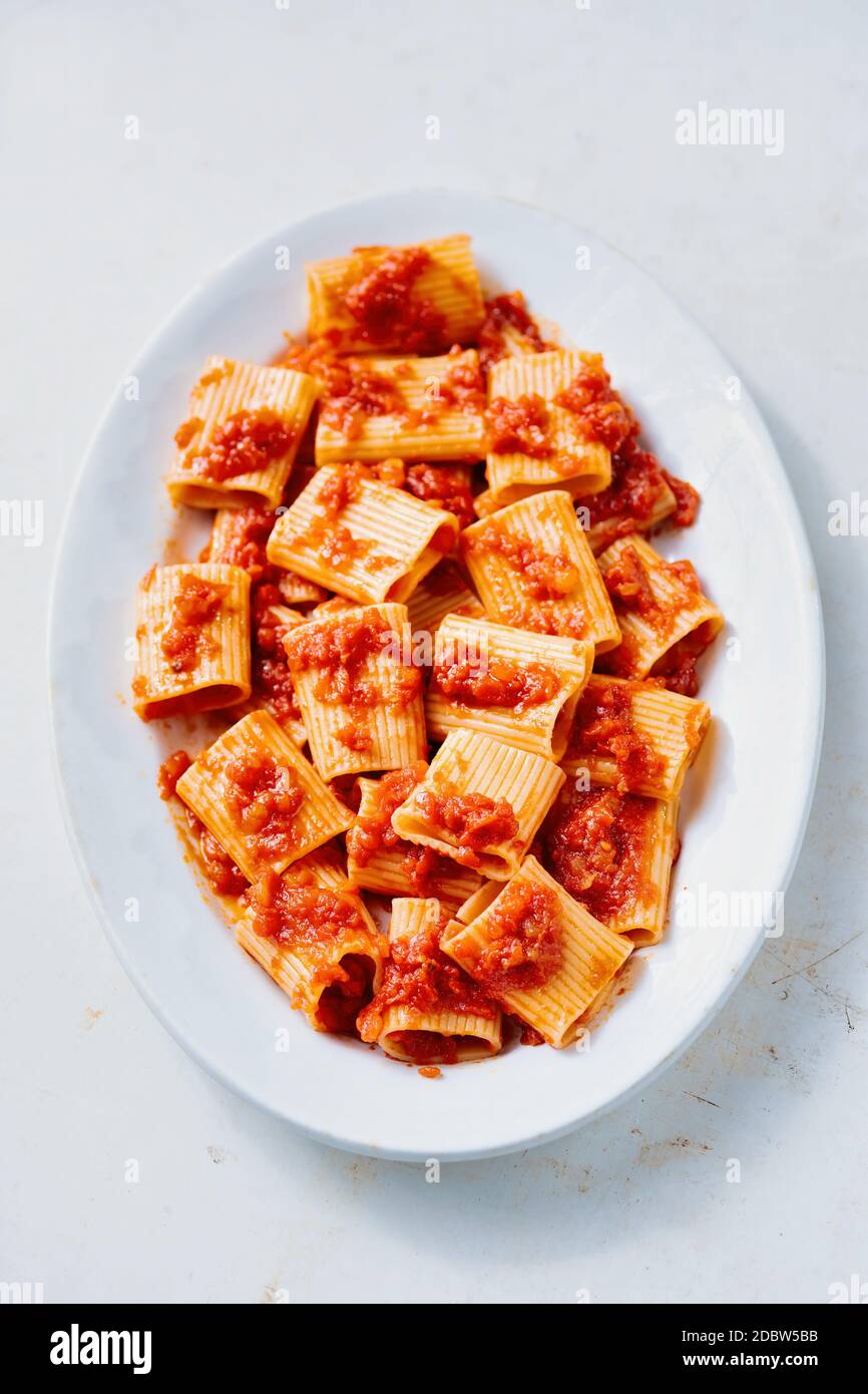 close up of a plate of rustic italian paccheri pasta in tomato sauce ...