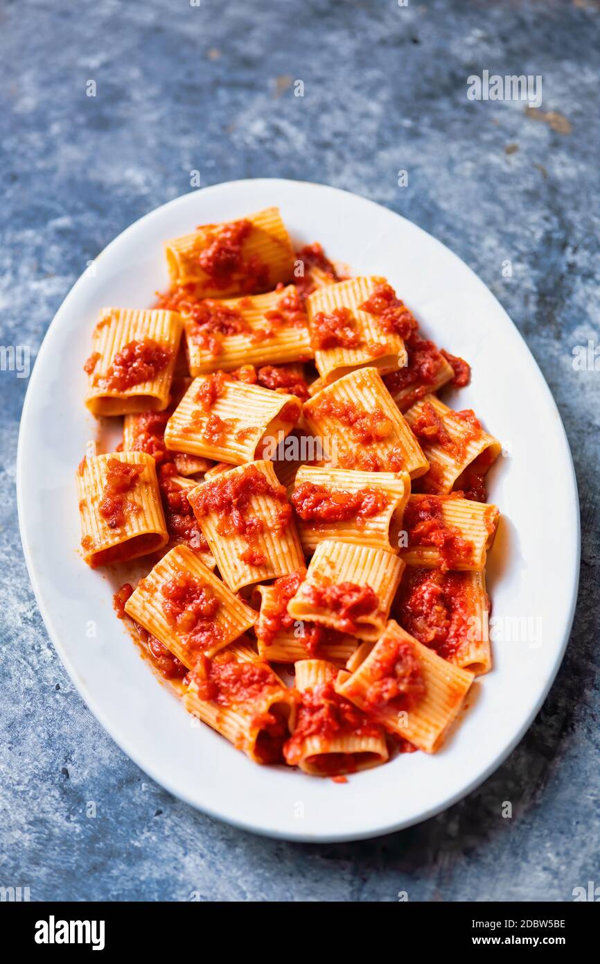 close up of a plate of rustic italian paccheri pasta in tomato sauce ...