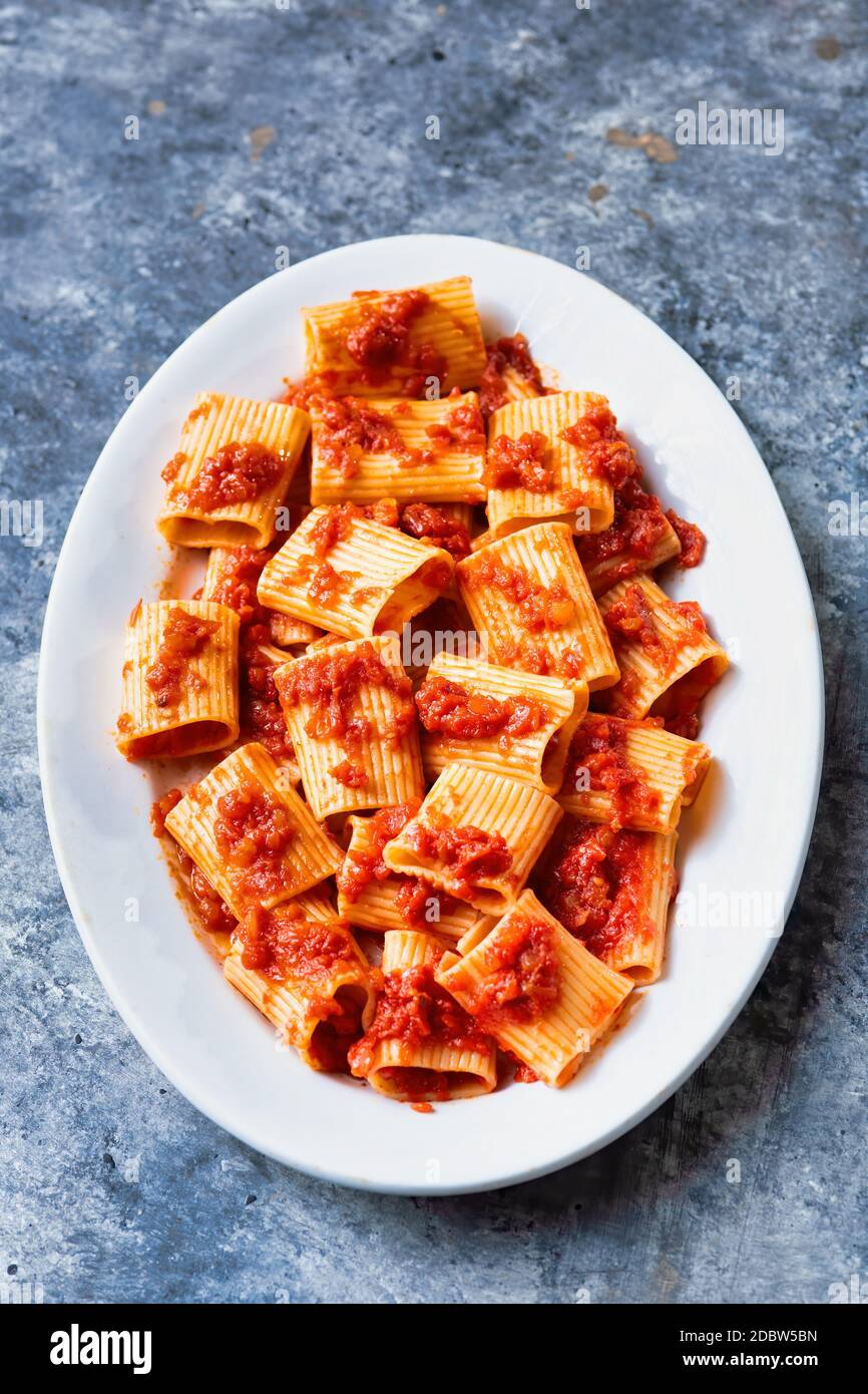 close up of a plate of rustic italian paccheri pasta in tomato sauce ...