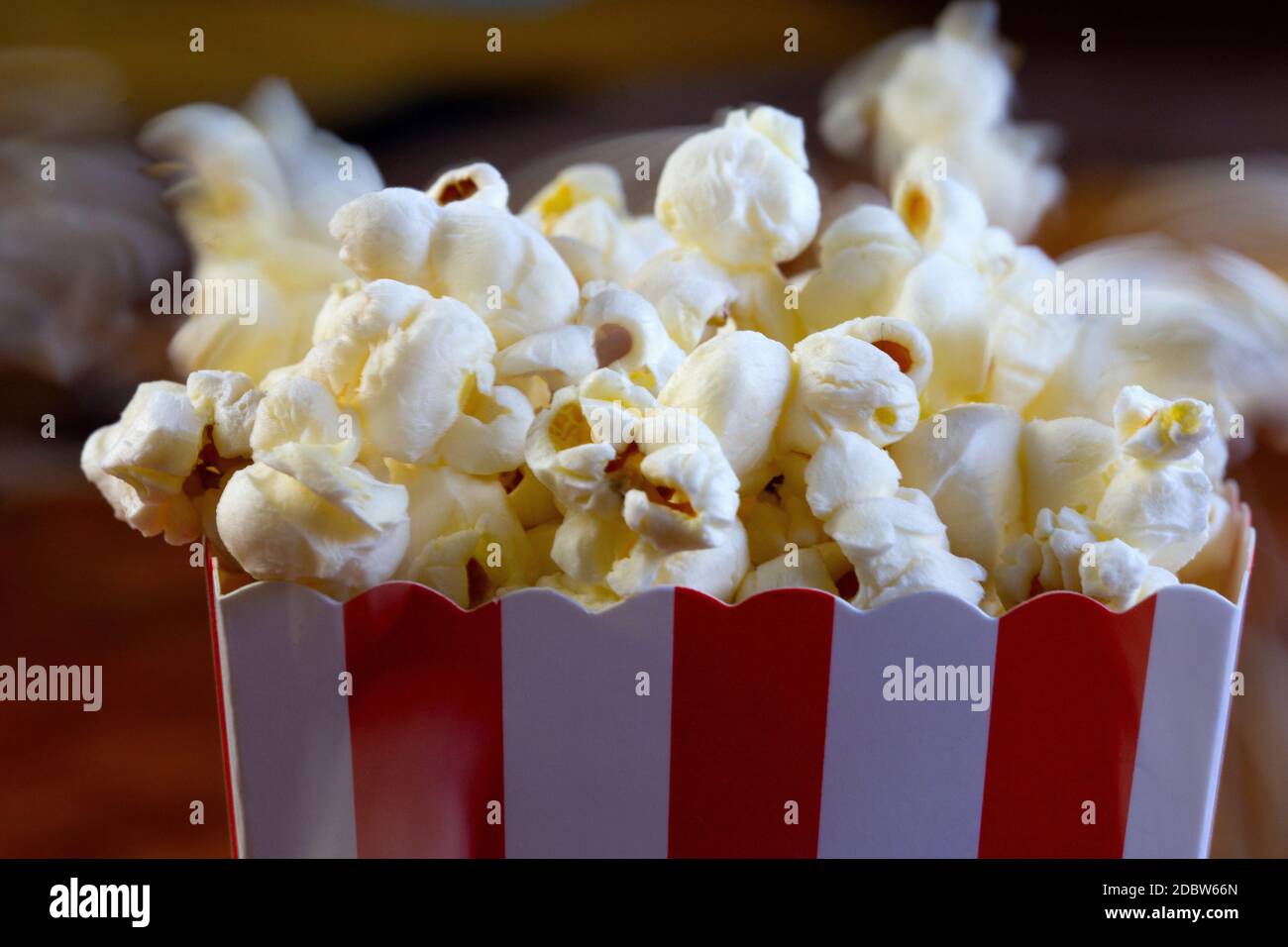 Popcorn flying out of cardboard box. red and white striped popcorn ...
