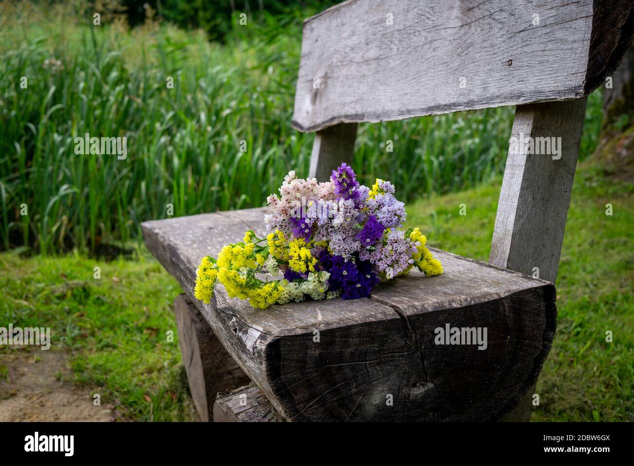 Posy of fresh spring flowers on a rustic weathered wooden bench ...