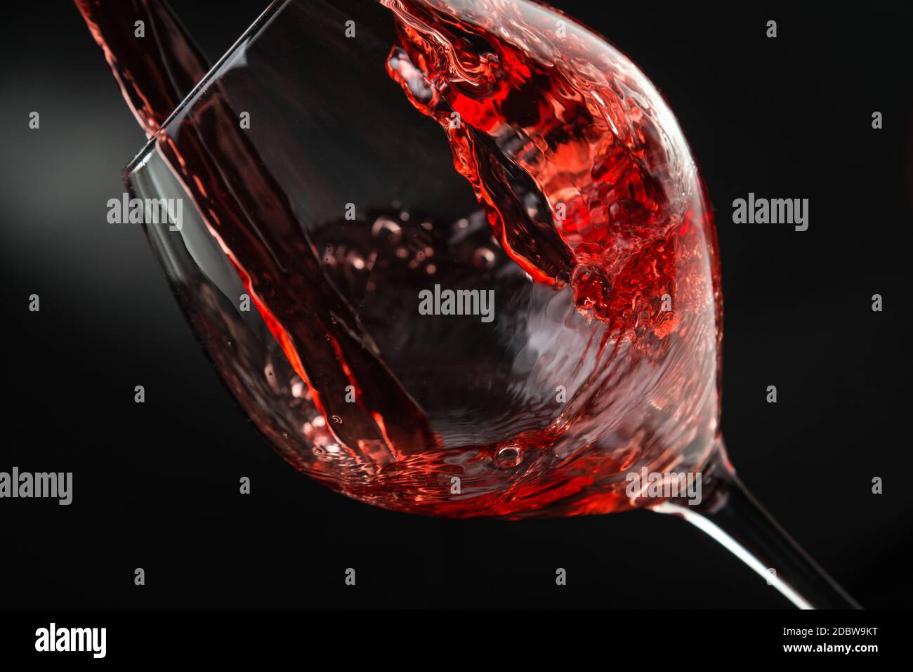 Pouring red wine, dark background Stock Photo - Alamy