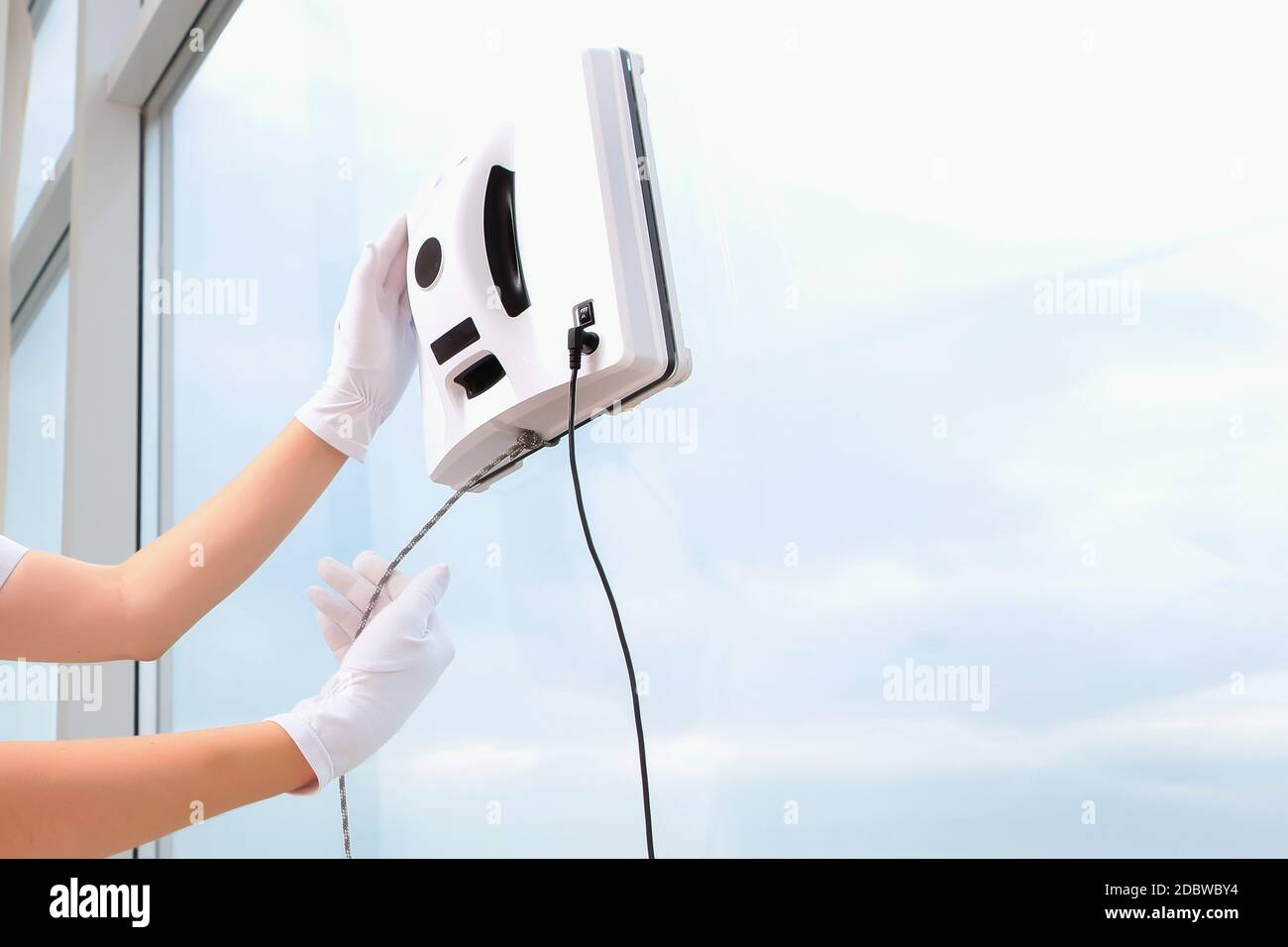 The maid installs a robot window cleaner on the glass. Clear window ...