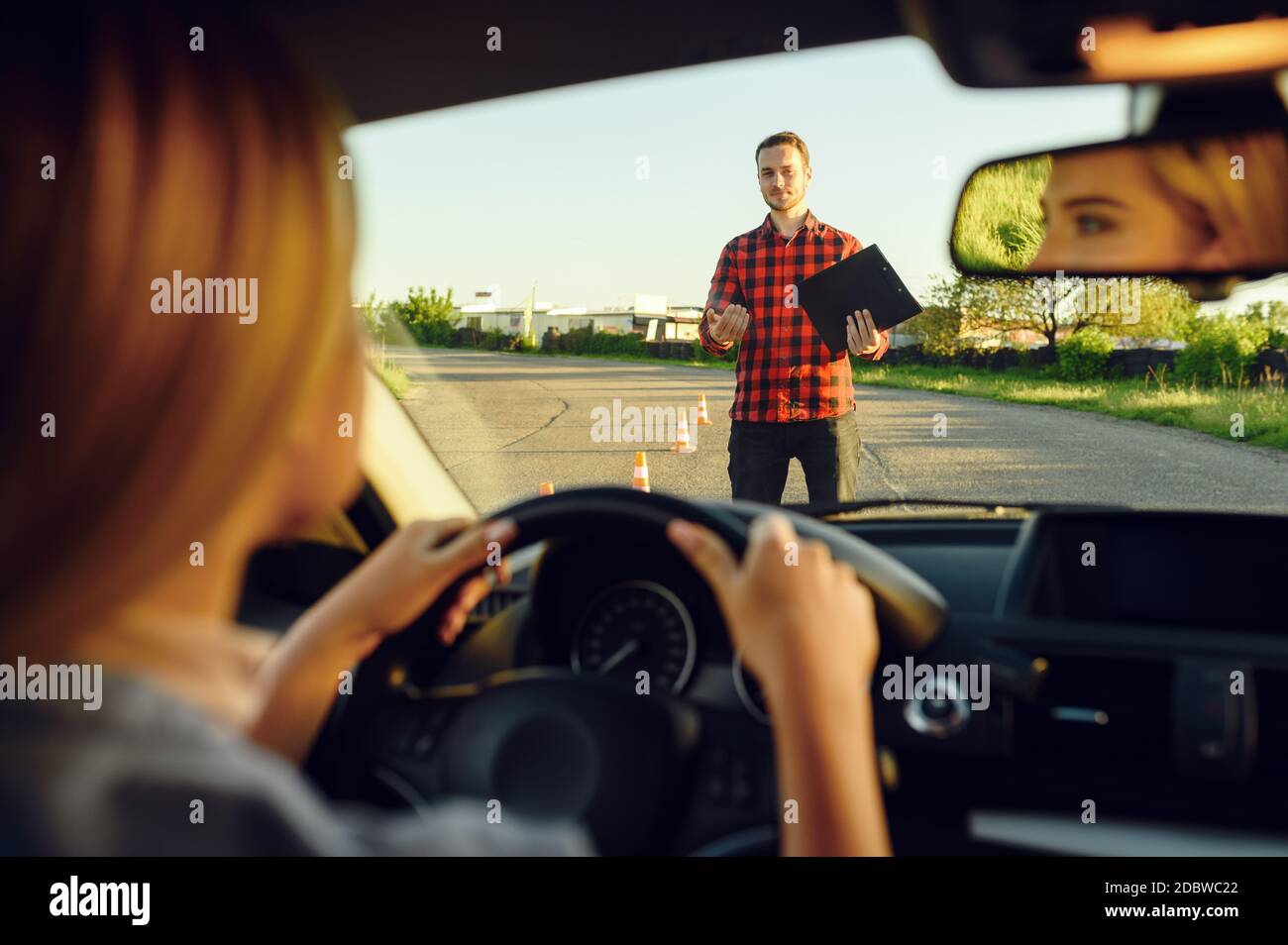 Woman in the car, instructor with checklist on road, driving school ...
