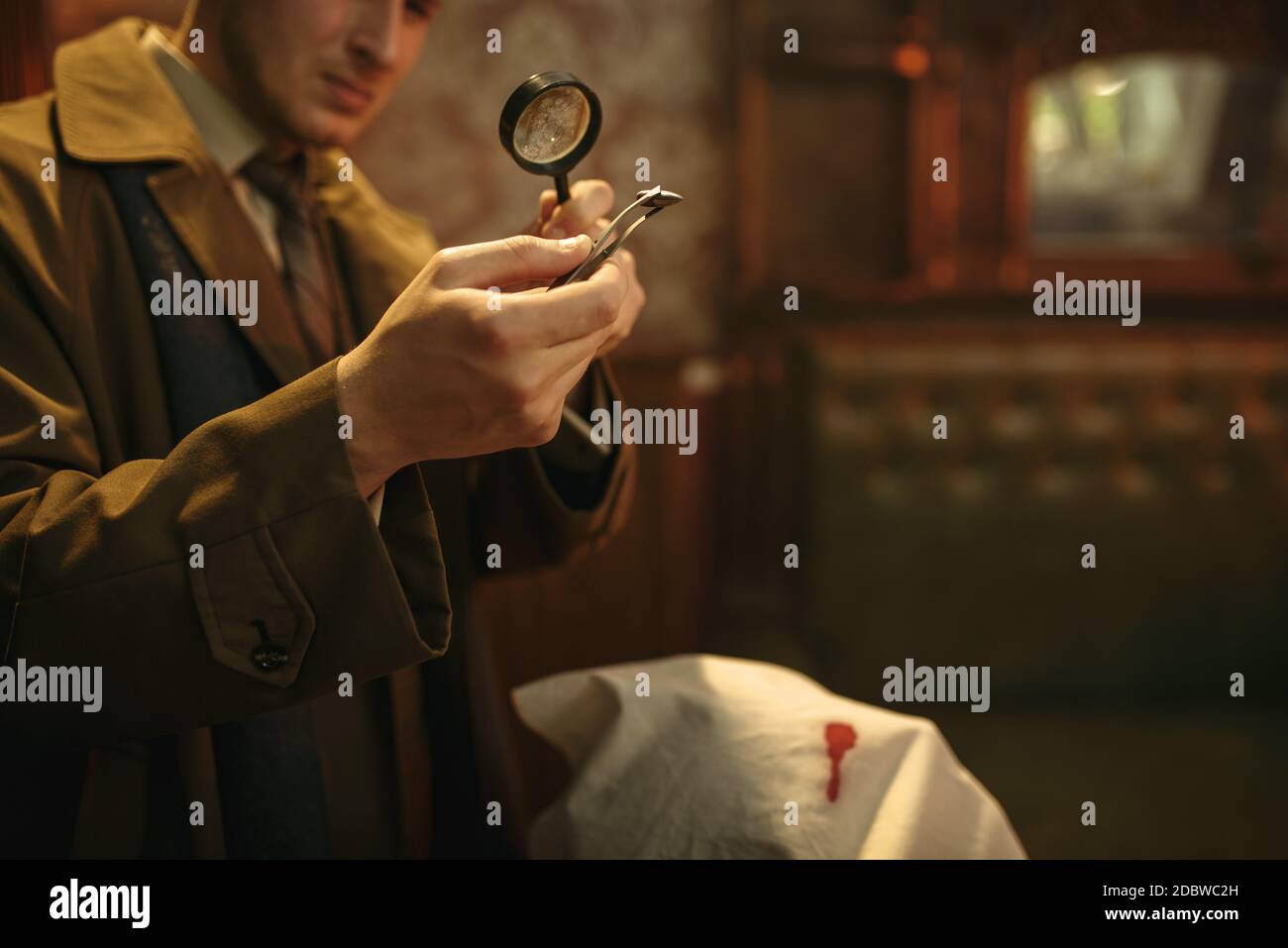 Male detective looks on evidence through magnifying glass at the crime ...