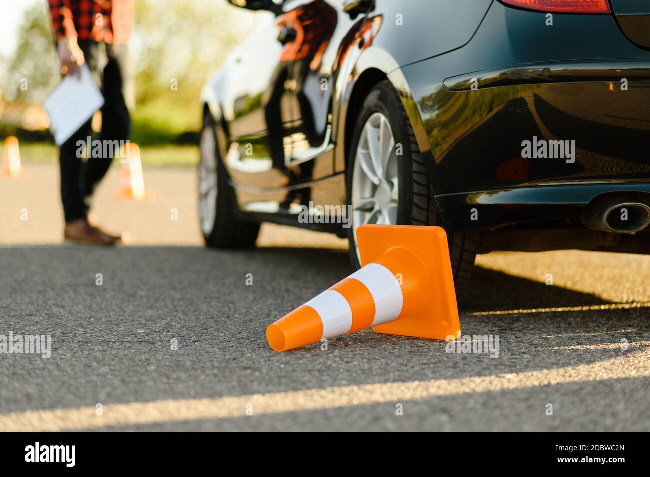 Male instructor at the car, downed traffic cone, lesson in driving ...