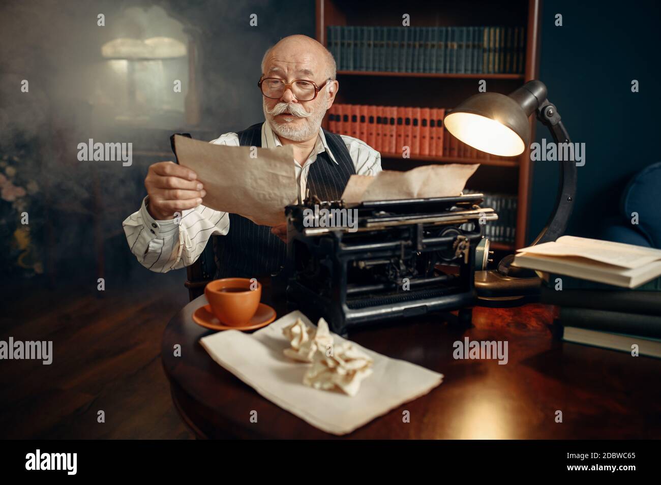 Elderly writer works on vintage typewriter in his home office. Old man ...