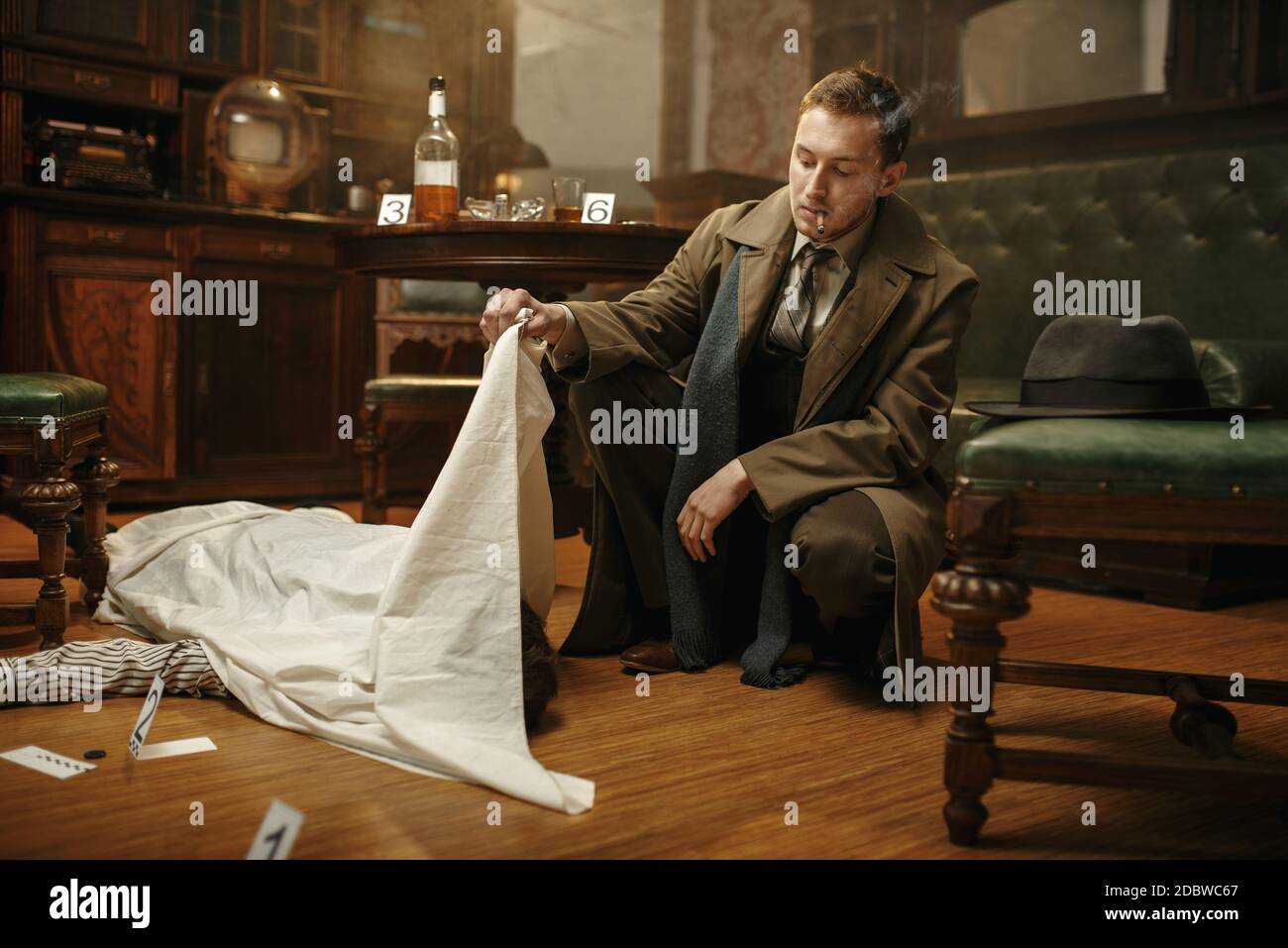 Male detective in coat looking on victim's body at the crime scene ...