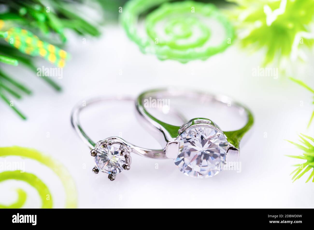 Closeup Diamond gem wedding rings with green leaves on white background ...