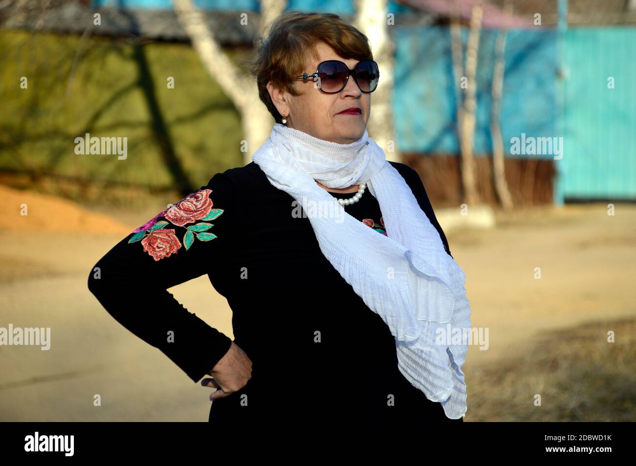 Portrait of stylish 67 year old woman in black blouse with flowers and ...