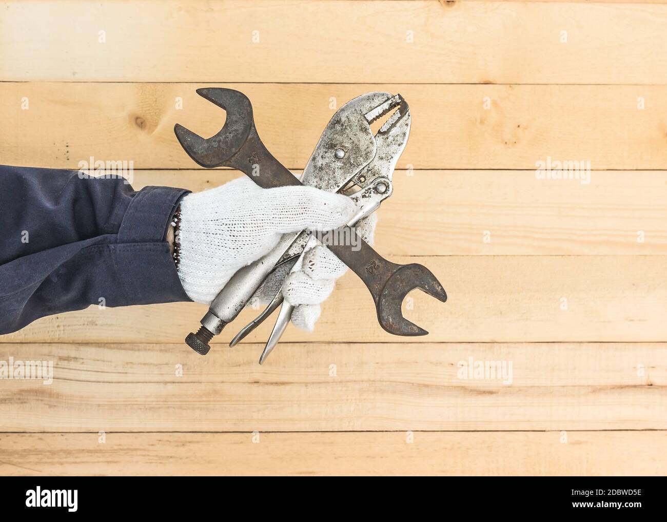 Working hand in glove holding a Spanner and Adjustable wrench with wall ...