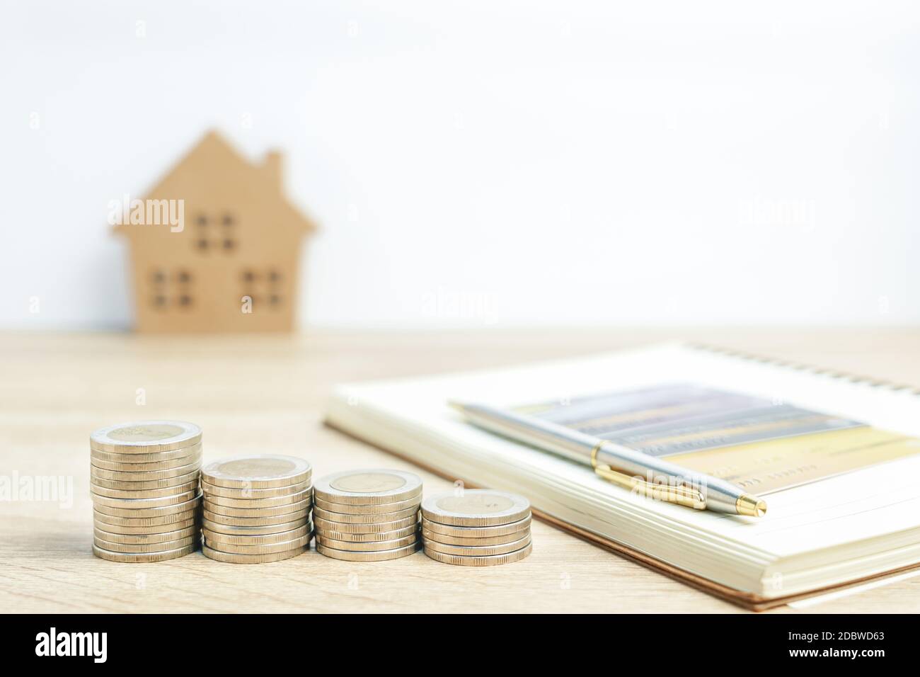 House model and notepad with coins on table for finance and banking ...