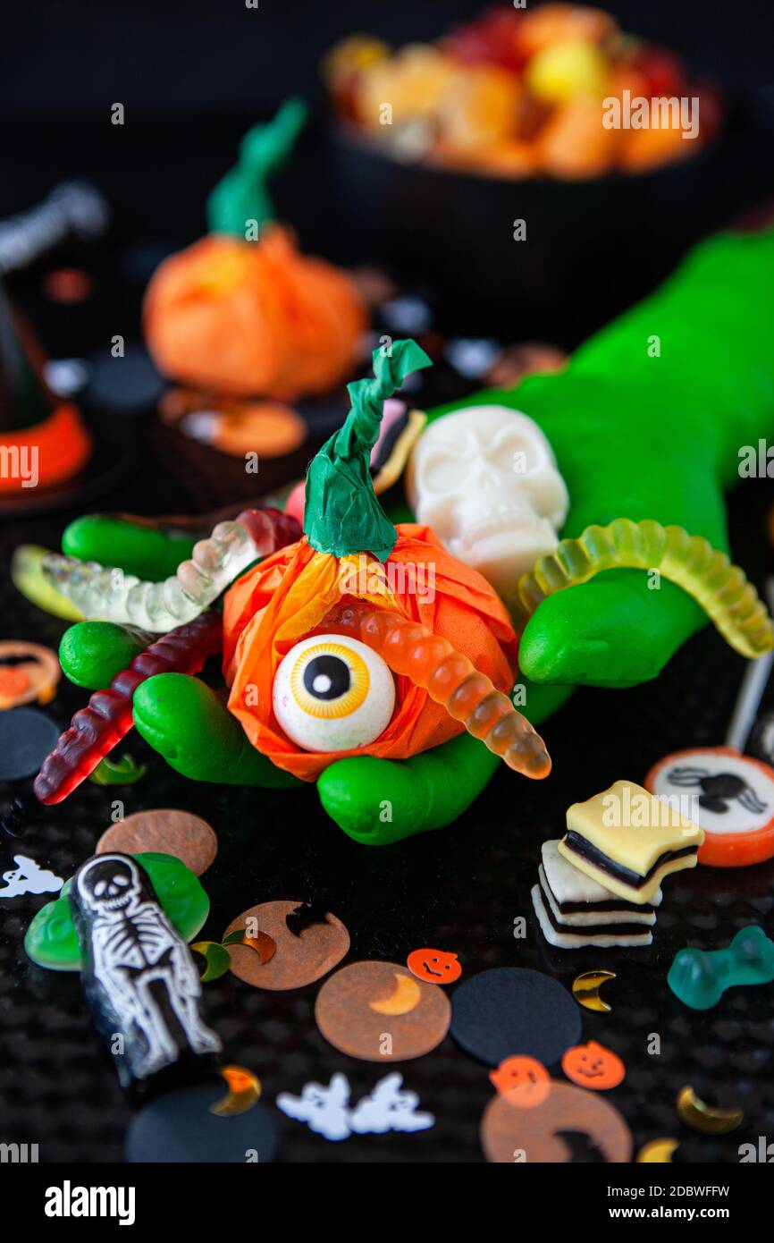 Green scary hand holding Halloween sweets and candy Stock Photo - Alamy