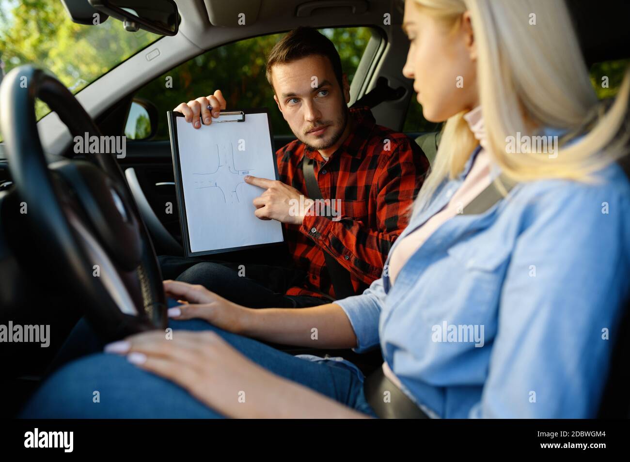 Woman and instructor with checklist in car, driving school. Man ...
