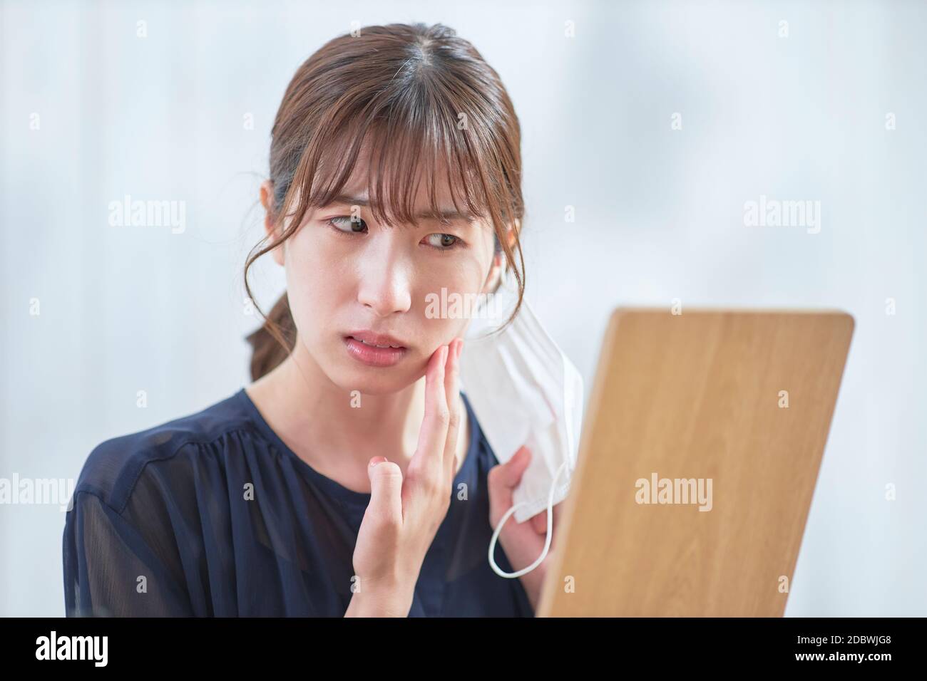 Young Woman Checking Her Face With A Mirror Stock Photo - Alamy