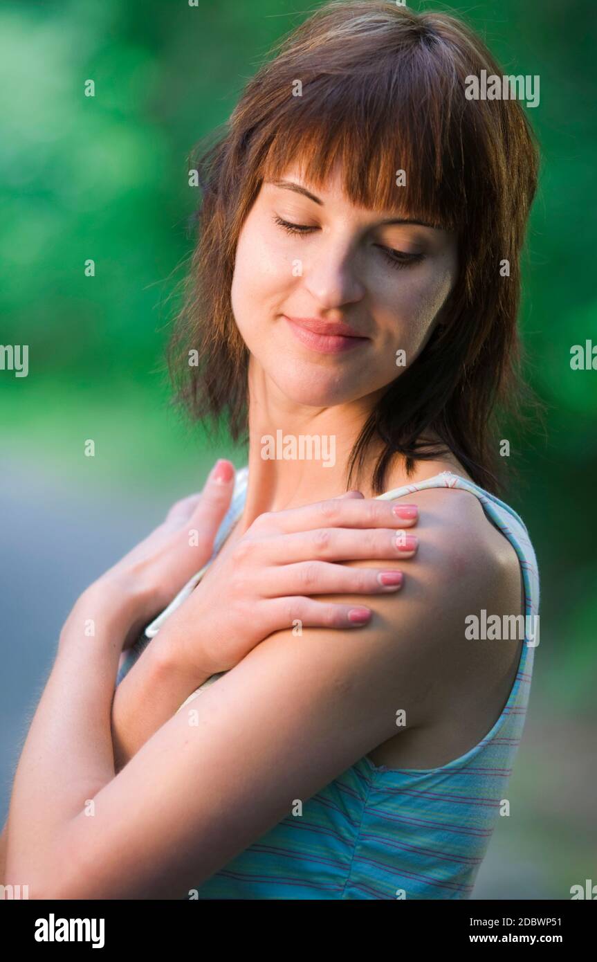 Lateral torso portrait of a young brunette woman in a top with arms ...