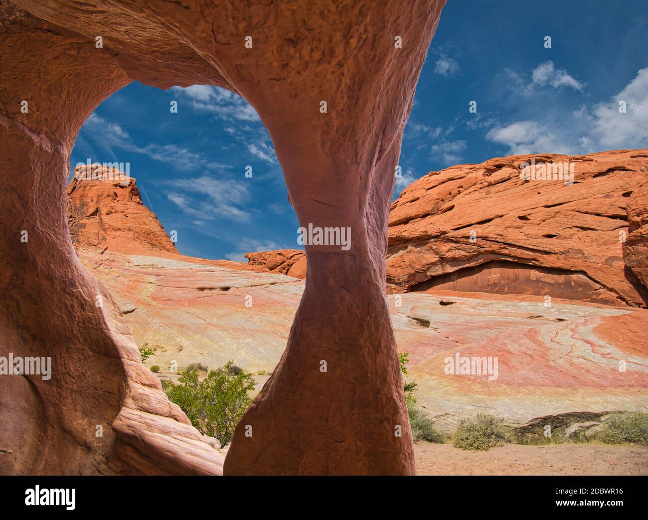 The view of the colourful rocks and plants through a large rock hole ...
