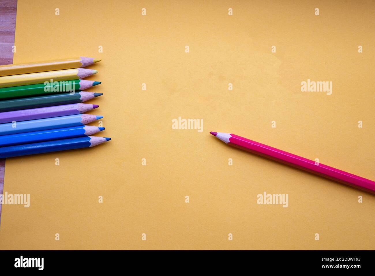 Colored pencils in Rainbow colors in a row on orange background, retro ...