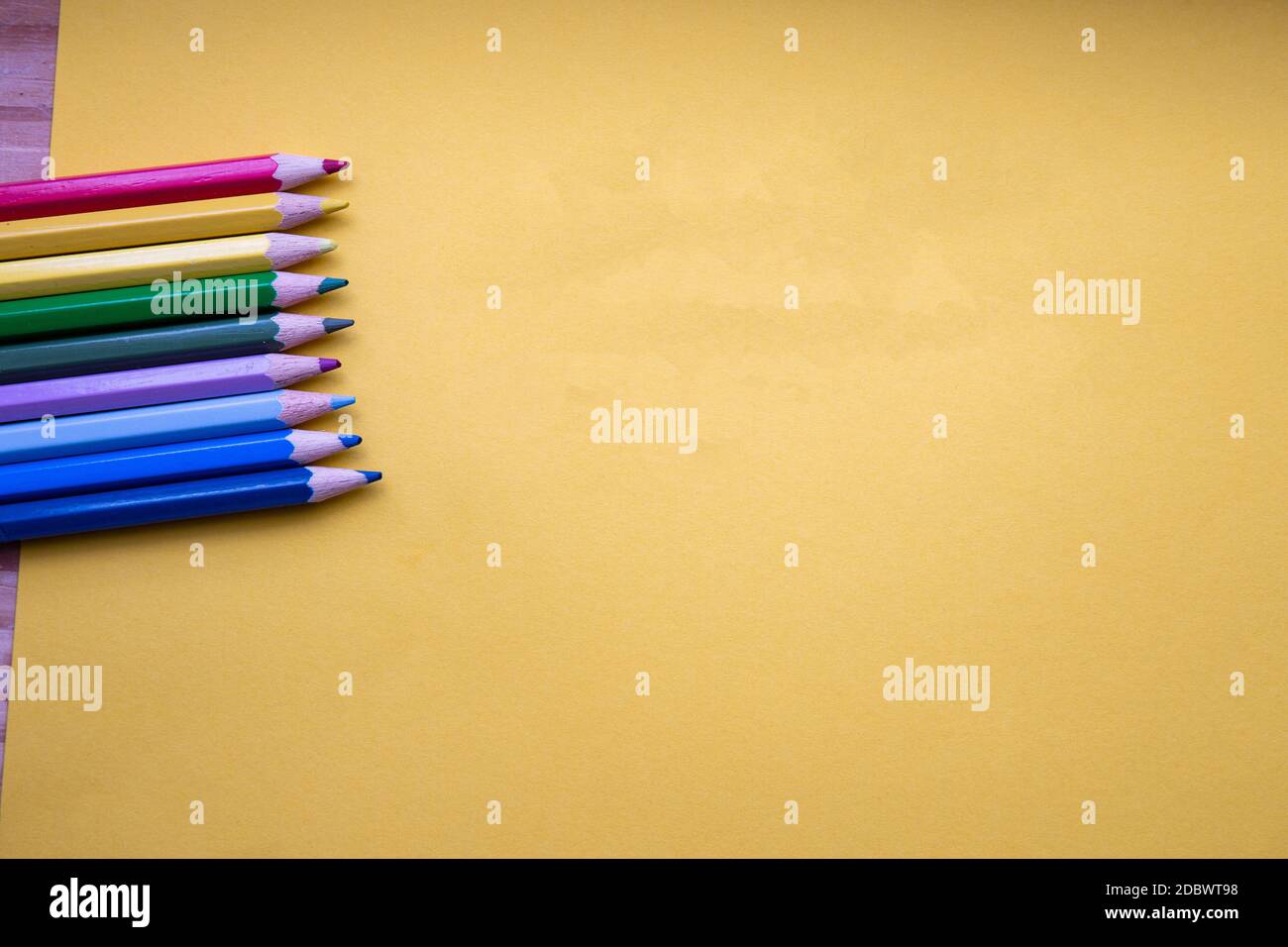 Colored pencils in Rainbow colors in a row on orange background, retro ...