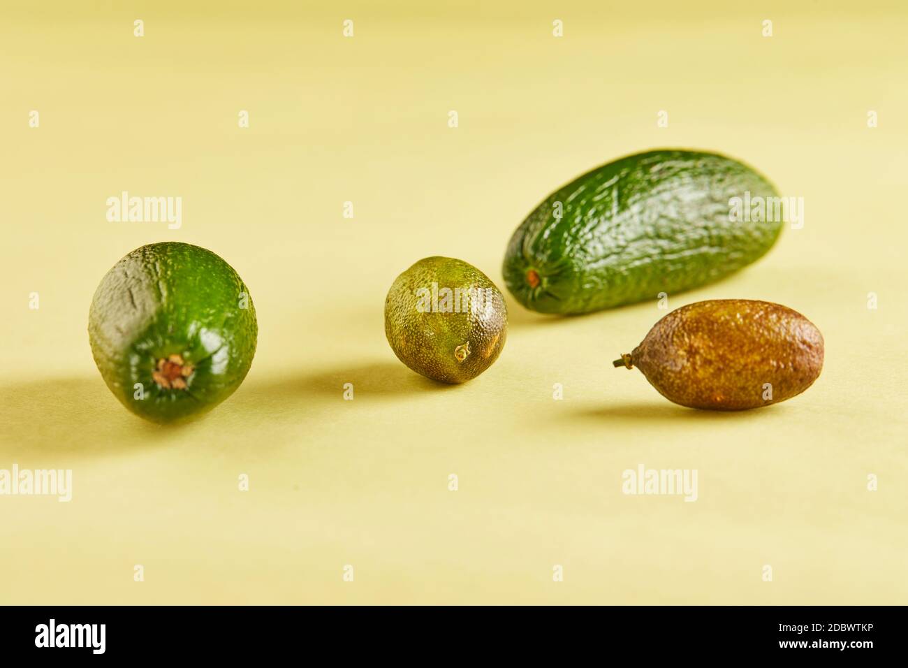 Ripe fresh mini avocados and mini lemons on a yellow background with a ...