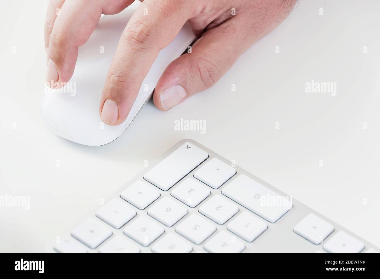 male hand clicking on a white mouse with a white keyboard on the right ...