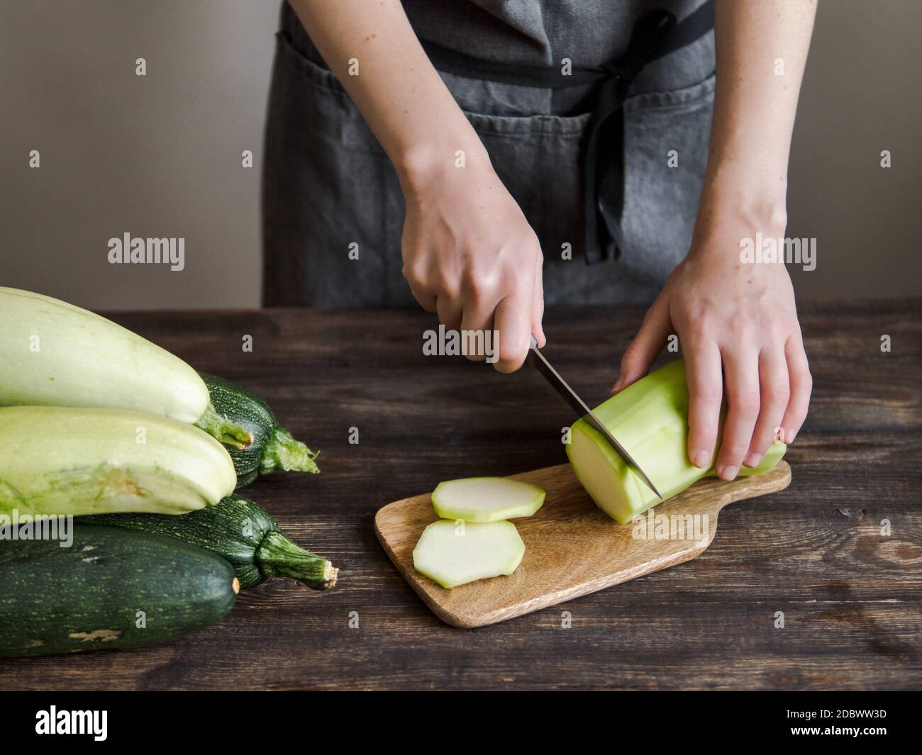 Zucchini harvest. Woman slices zucchini on wooden table. Farm organic ...