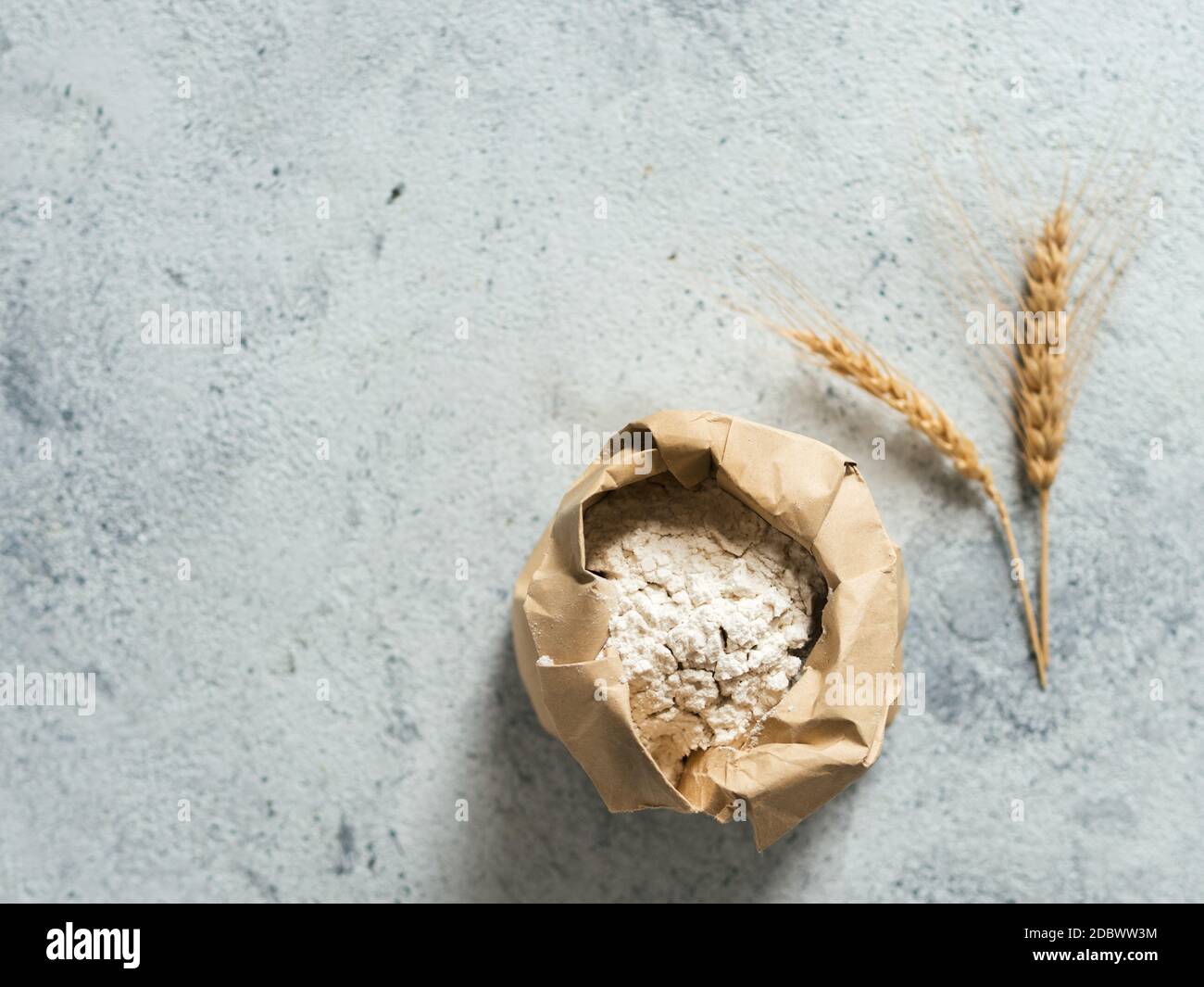 Wheat flour in paper bag and spikes over gray cement background. Food ...