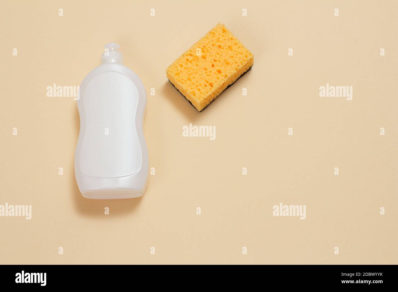 Plastic bottle of dishwashing liquid and a sponge on the beige ...