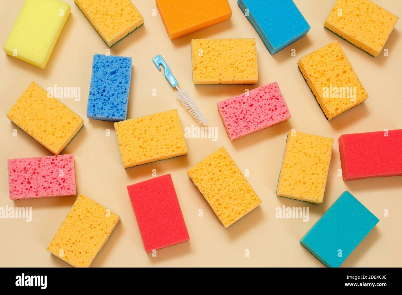 Sponges of different colors and a small brush on the beige background ...