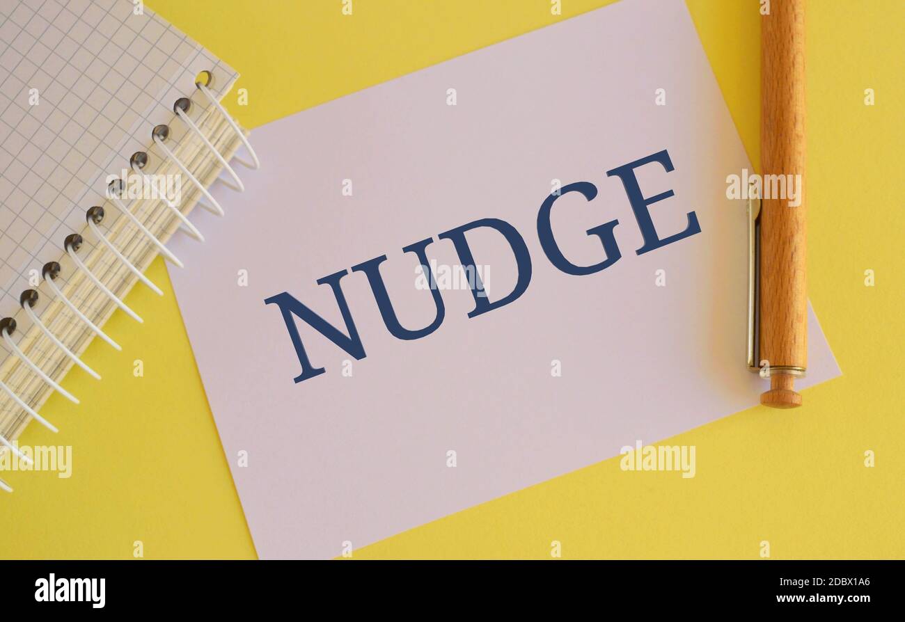 White paper with text Nudge on yellow background. Pushing gently ...