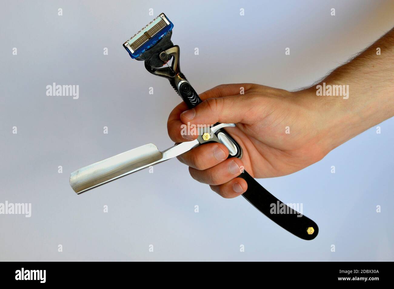 Male hand holding black straight razor and classic razor isolated on ...