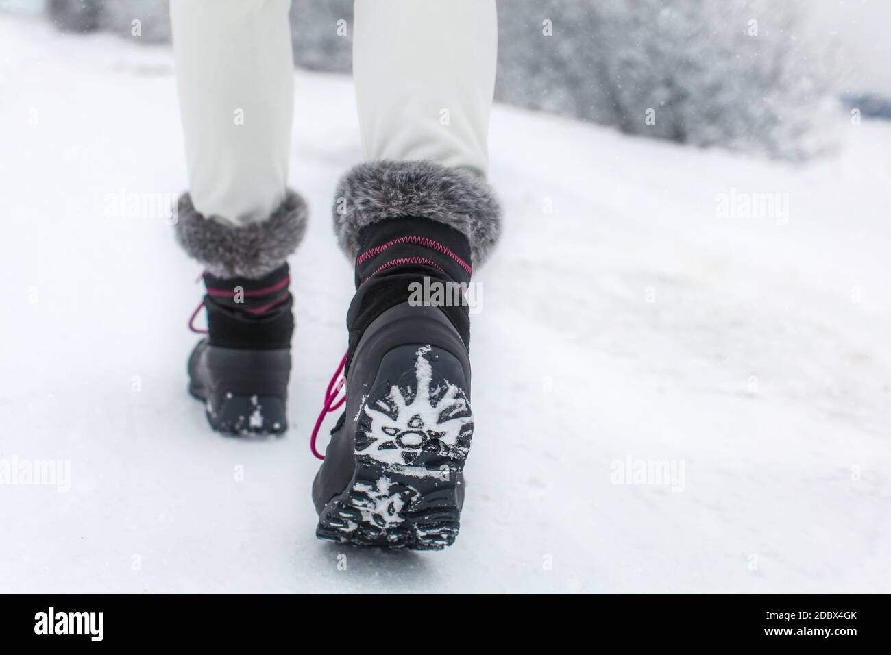 Detail of woman lifting her black and gray snow boot with faux fur and ...
