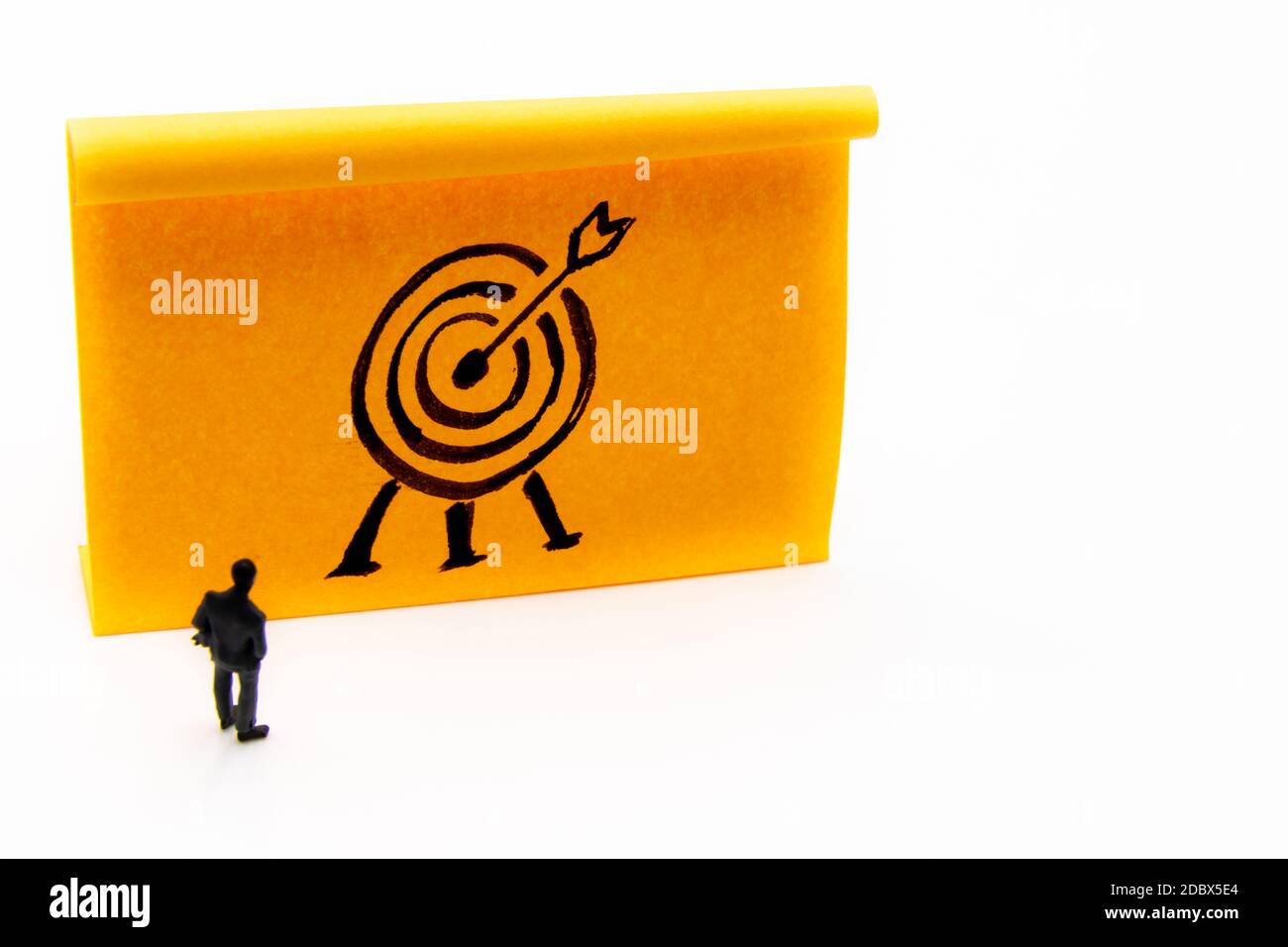 Miniature figurine posed as businessman in front of target hand drawn ...