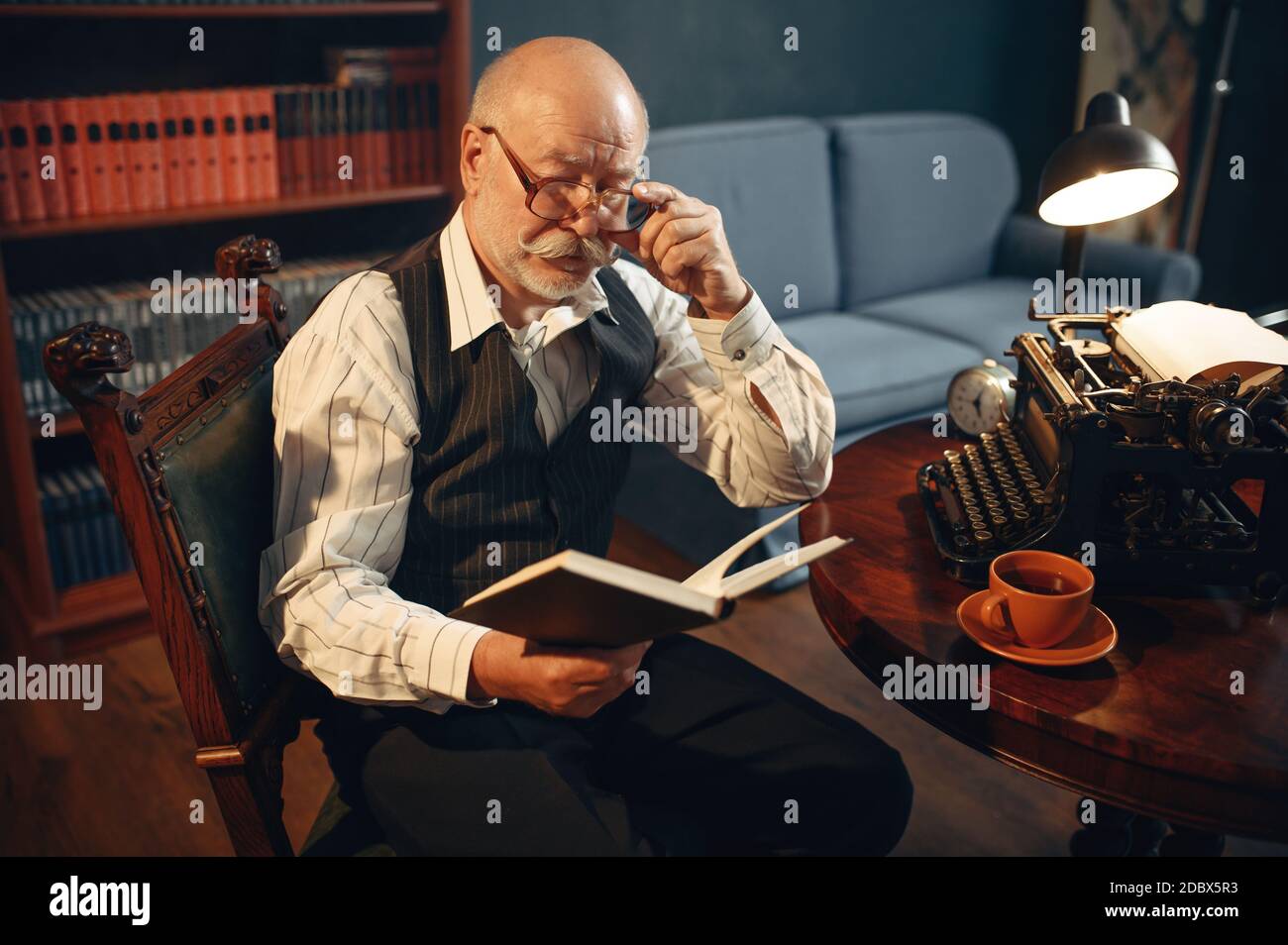 Elderly writer reads his work at vintage typewriter in home office. Old ...