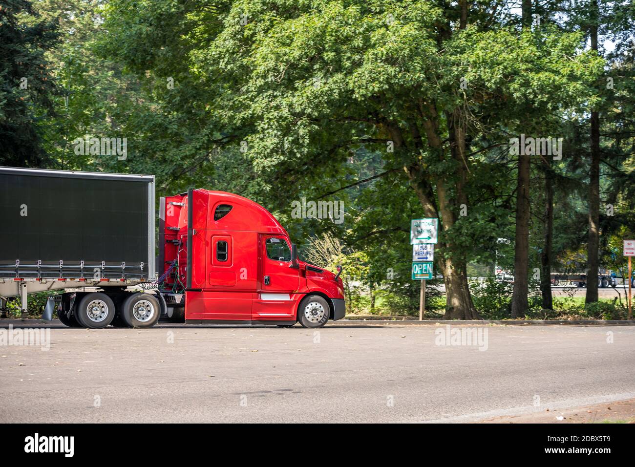 Bright red long haul industrial big rig semi truck tractor with covered ...