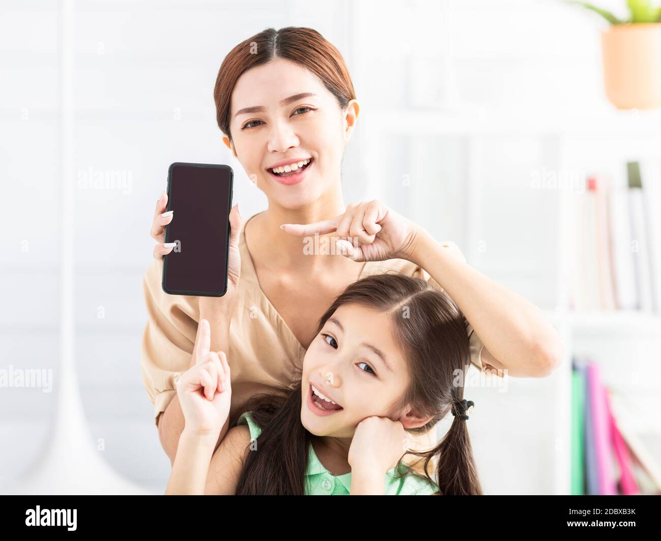 happy mother and daughter showing the mobile phone Stock Photo - Alamy