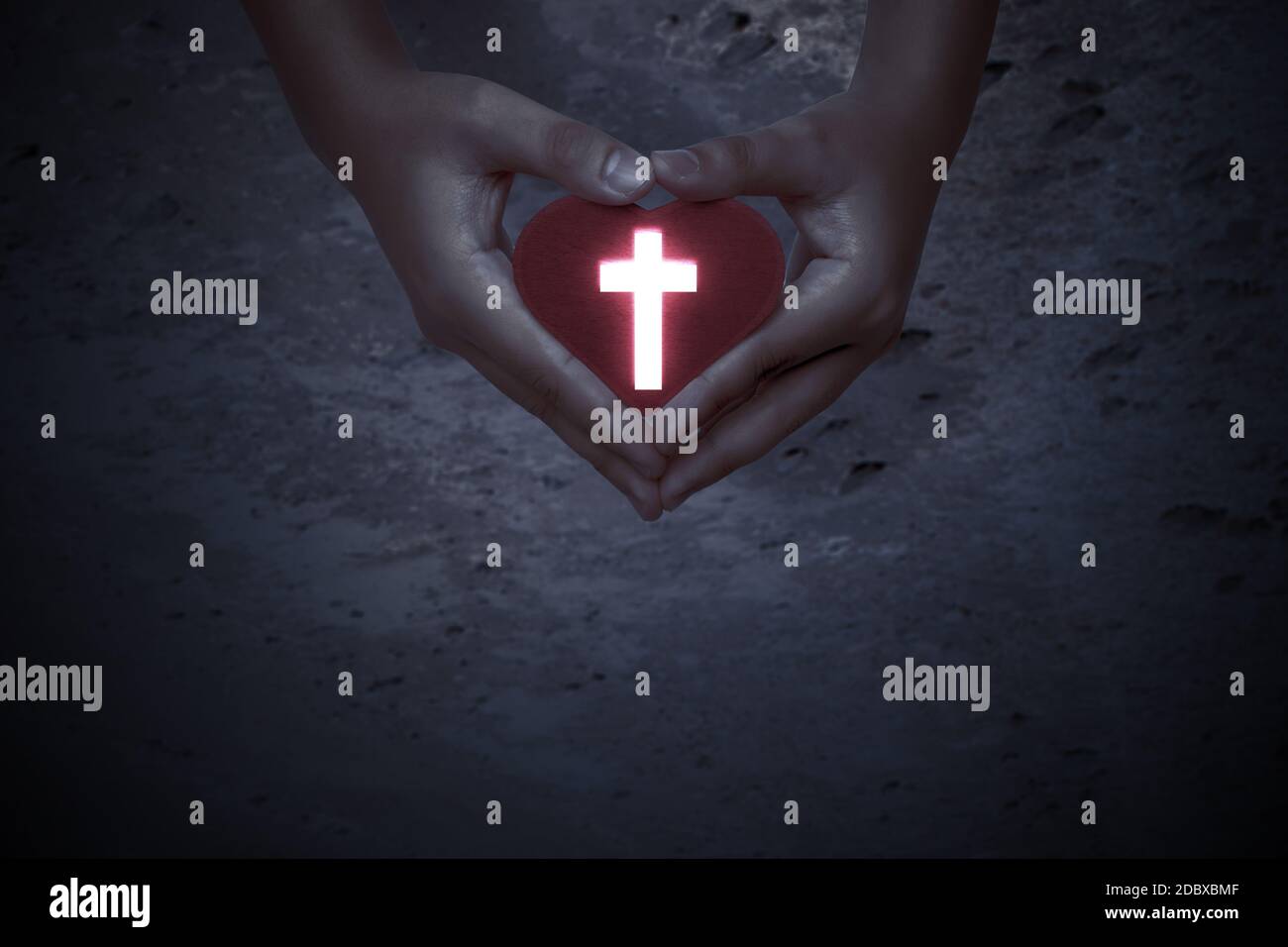 Human hands showing red heart with Christian cross with black wall ...