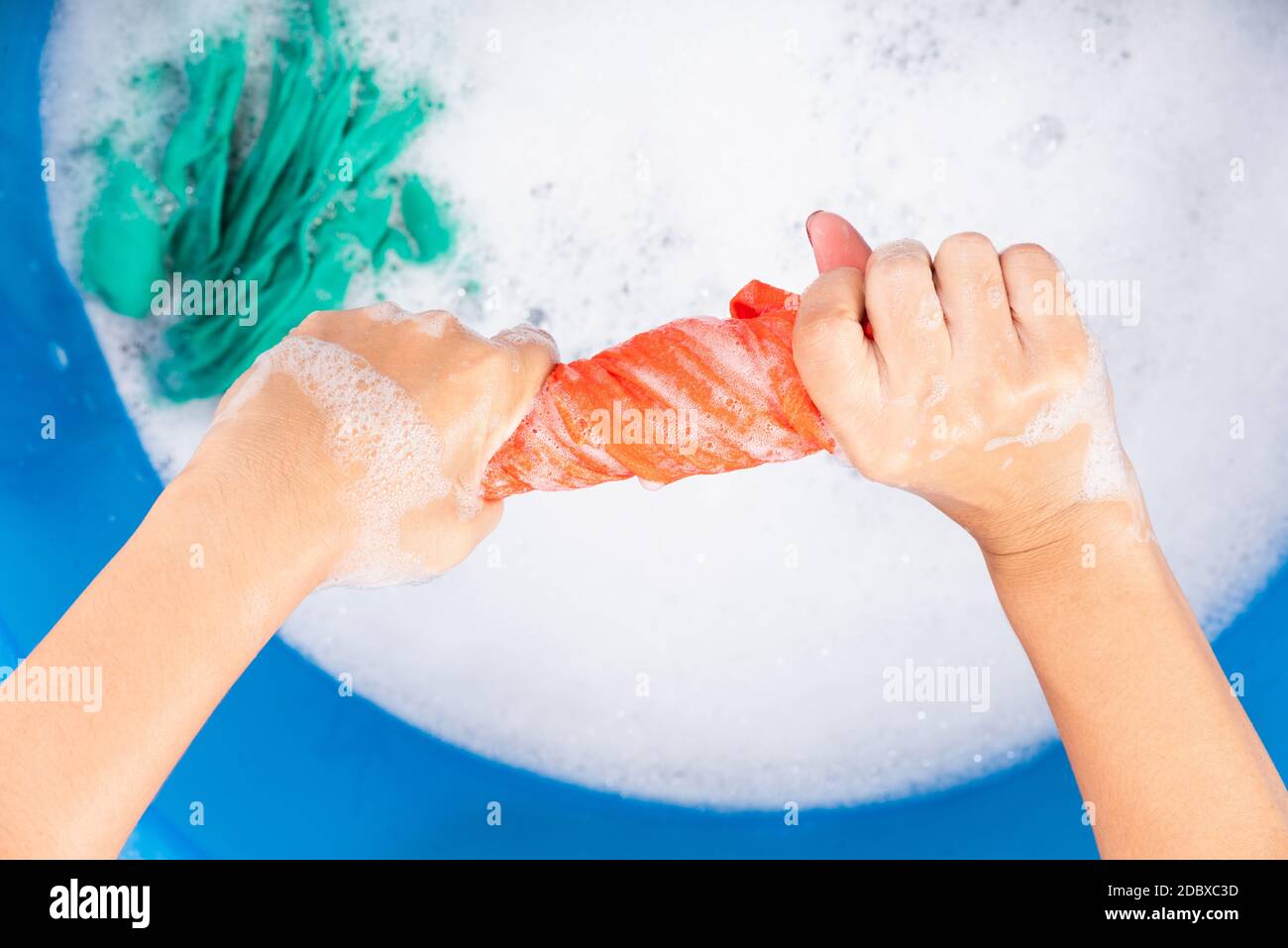 Closeup young Asian woman use hands washing color clothes in basin ...