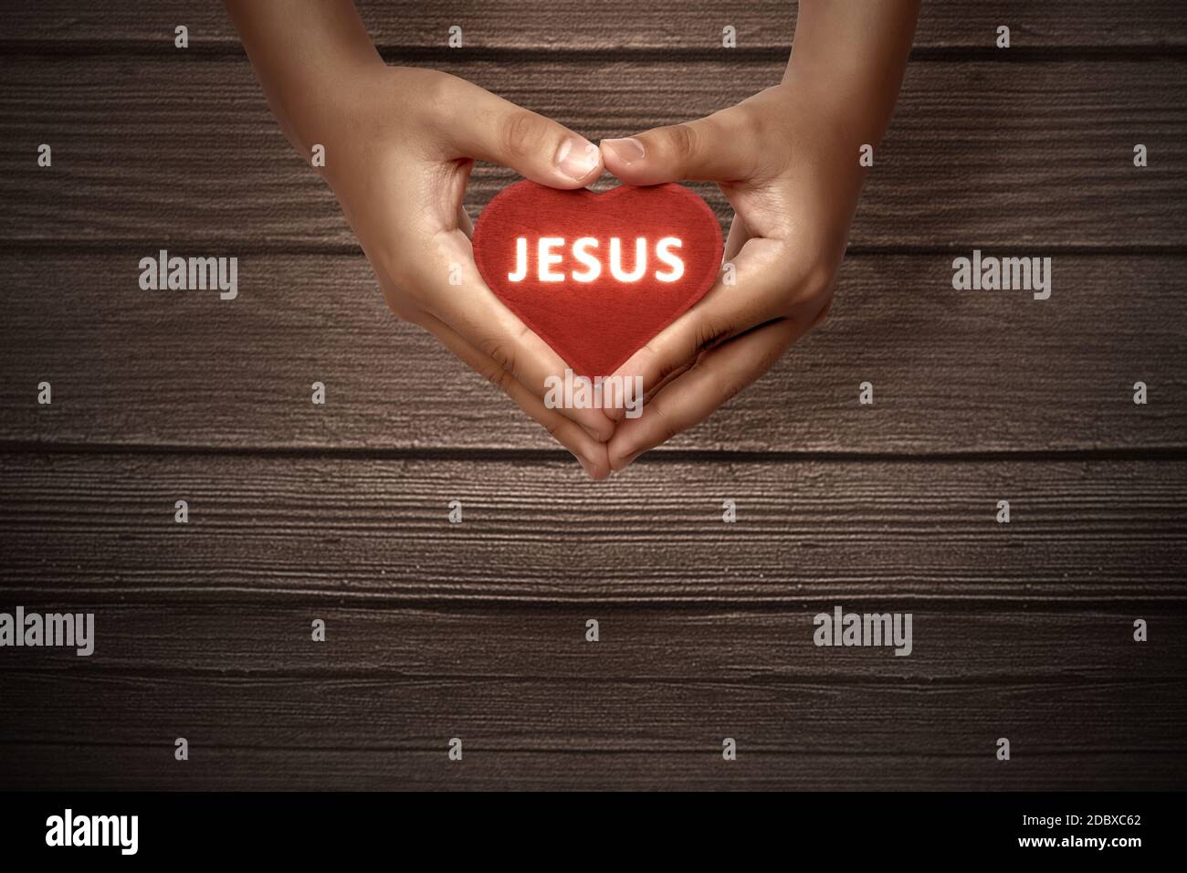 Human hands showing red heart with Jesus text with wooden background ...